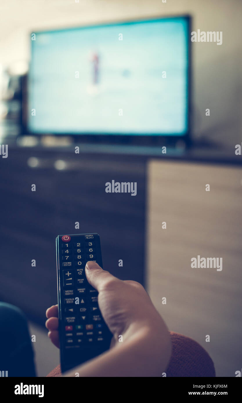 Hand hold TV remote control. TV on the background Stock Photo - Alamy