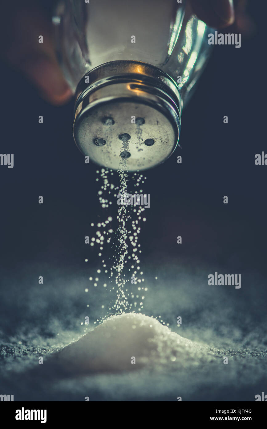 Adding salt. Backlight to salt from salt shaker. Close up Stock Photo ...