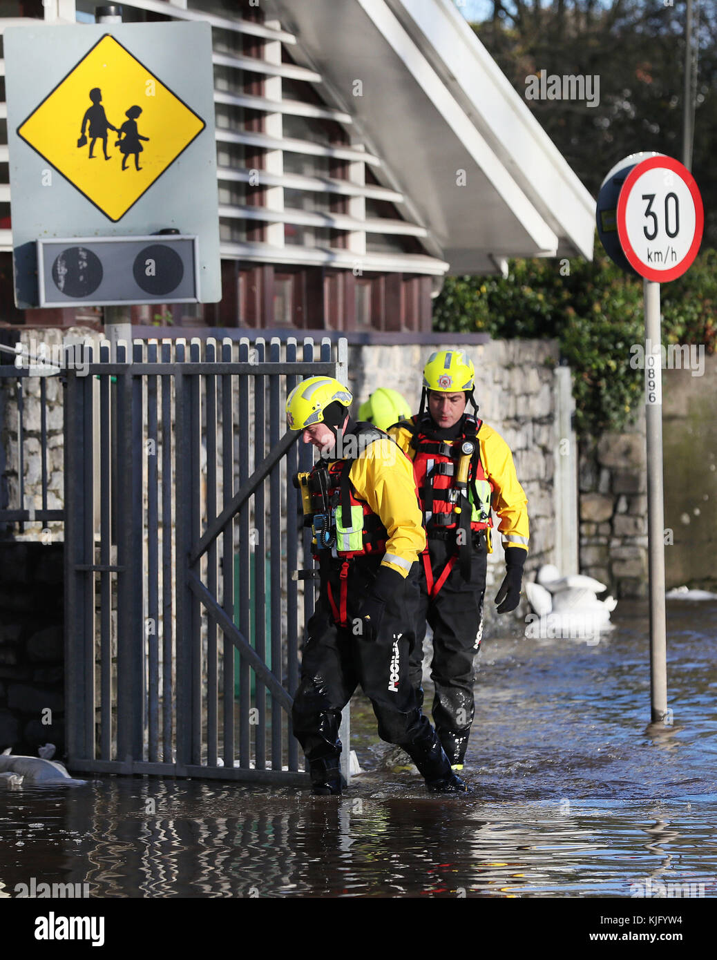 Members of the fire service walk through flood water in Mountmellick ...