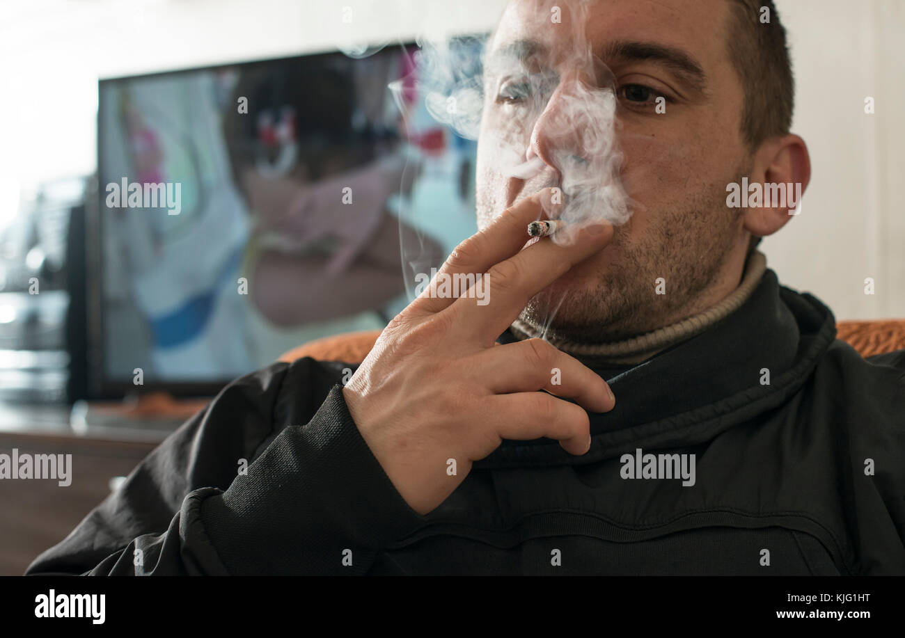 Man smokes a cigarette in the house. Close up Stock Photo - Alamy
