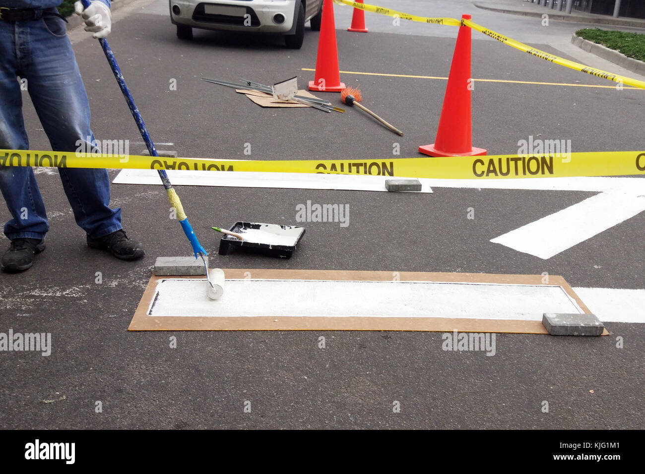 Worker marking white lines of pedestrian road crossing ZEBRA. Caution ...