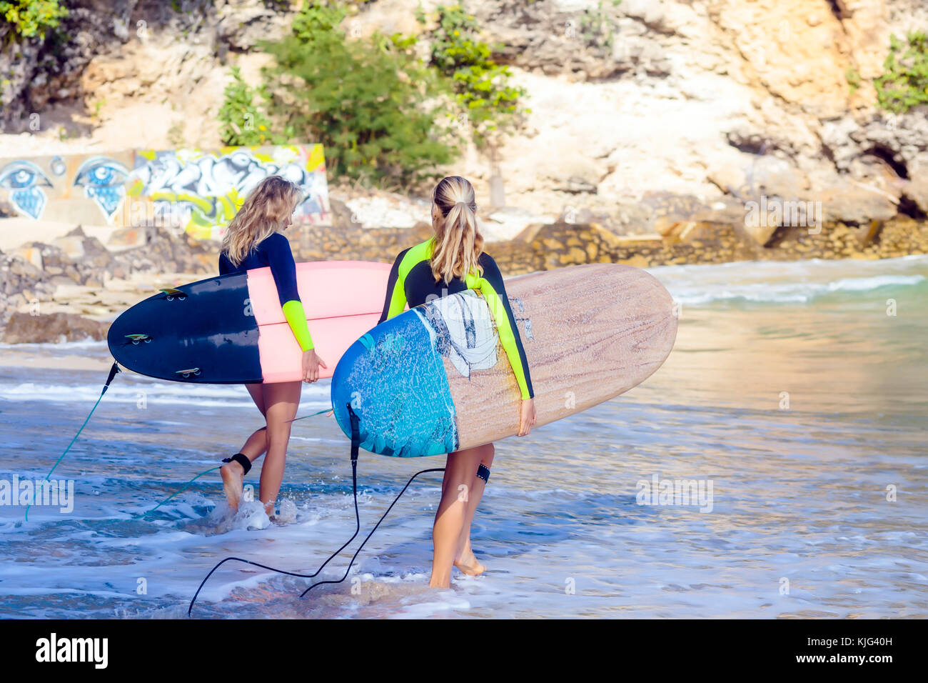 Indonesia, Bali, two women carrying surfboards at the sea Stock Photo ...
