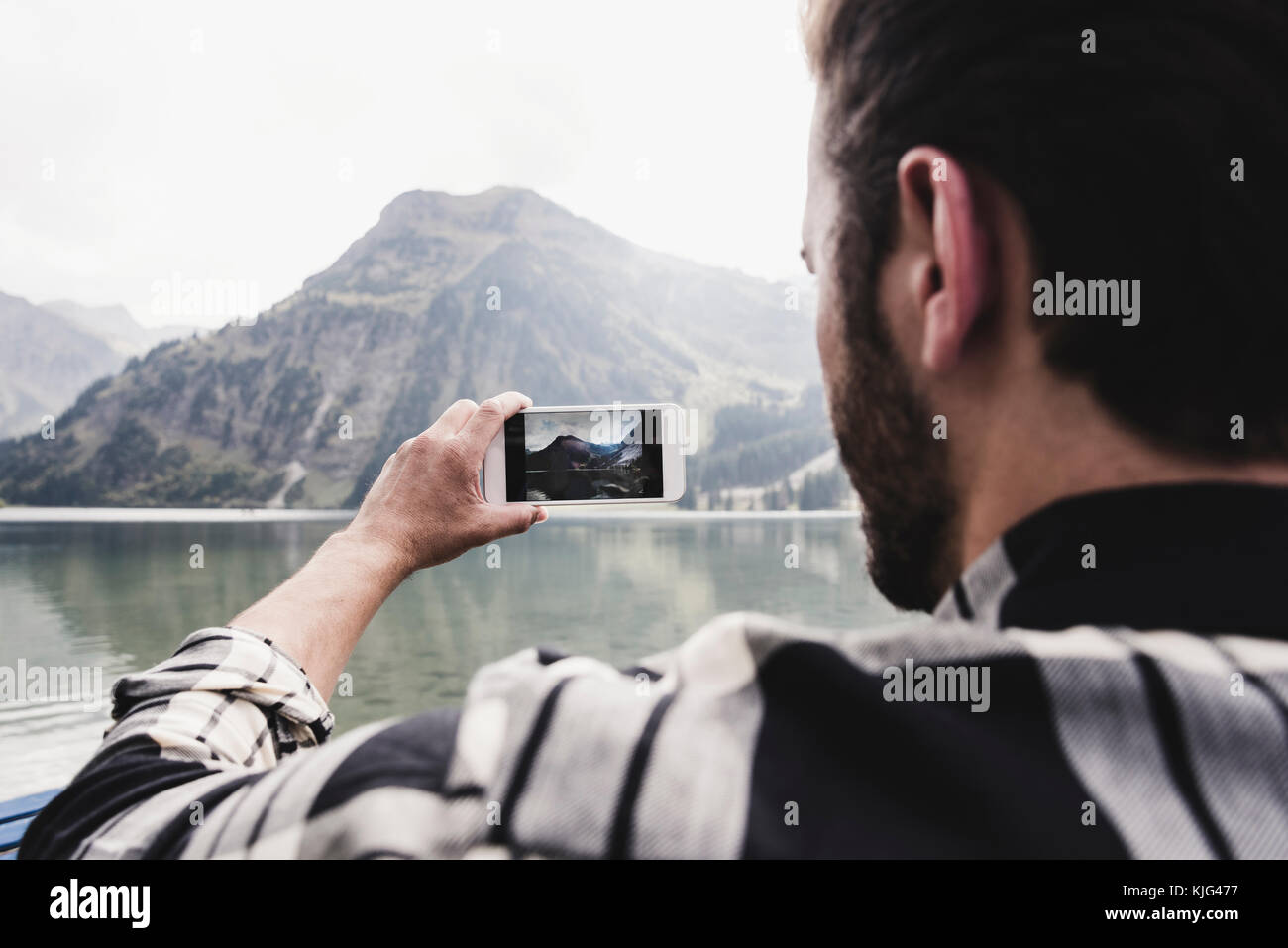Austria, Tyrol, Alps, man taking cell phone picture of mountainscape ...