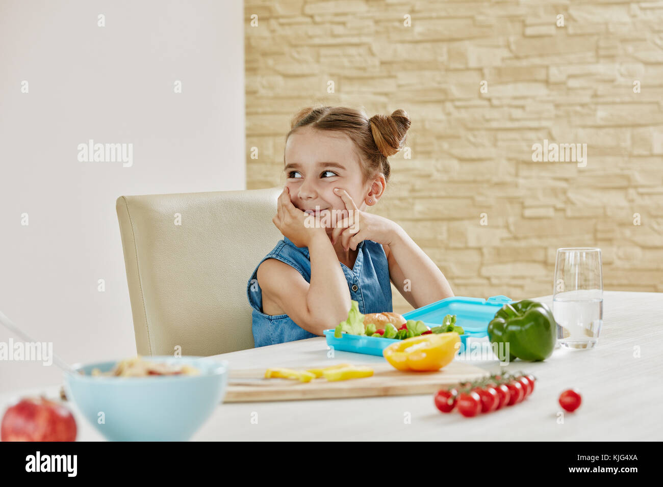 Smiling girl at table packing lunchbox with healthy food Stock Photo ...