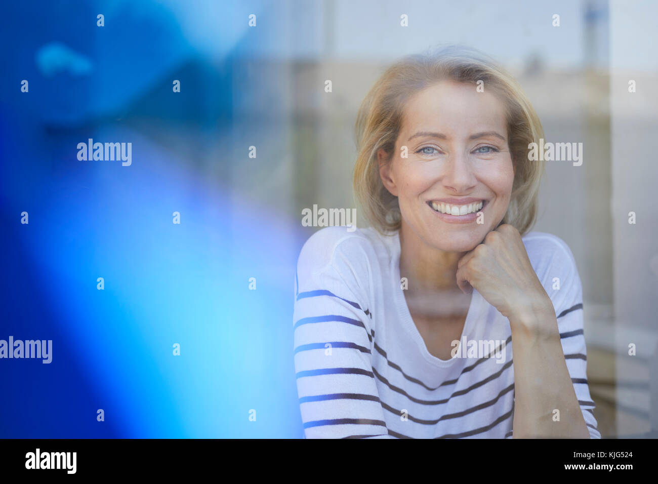 Portrait of laughing blond woman behind window pane Stock Photo - Alamy