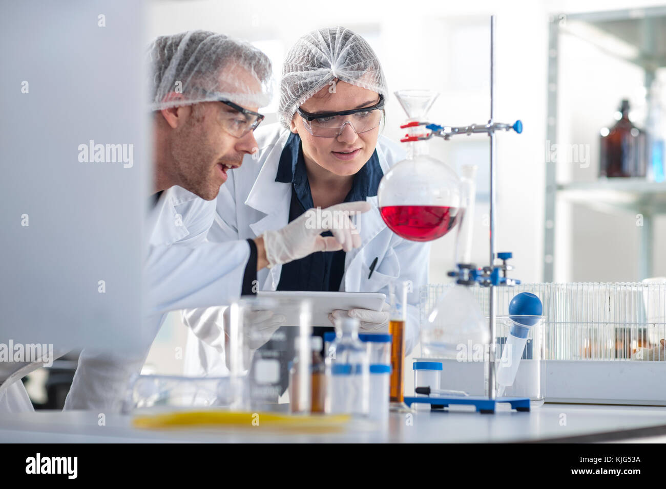 Two scientists working in lab together looking at flask Stock Photo - Alamy