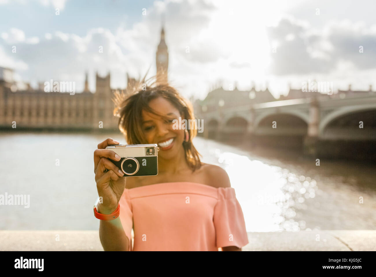UK, London, beautiful woman taking a picture near Westminster Bridge ...