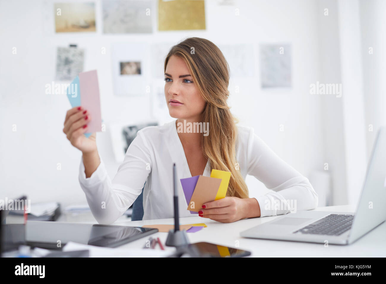 Young woman looking at notes at desk in office Stock Photo - Alamy