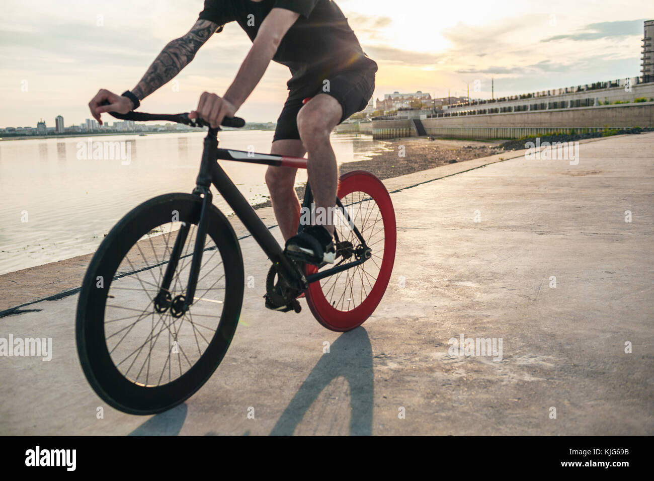 Young man riding fixie bike at the waterfront at sunset Stock Photo - Alamy