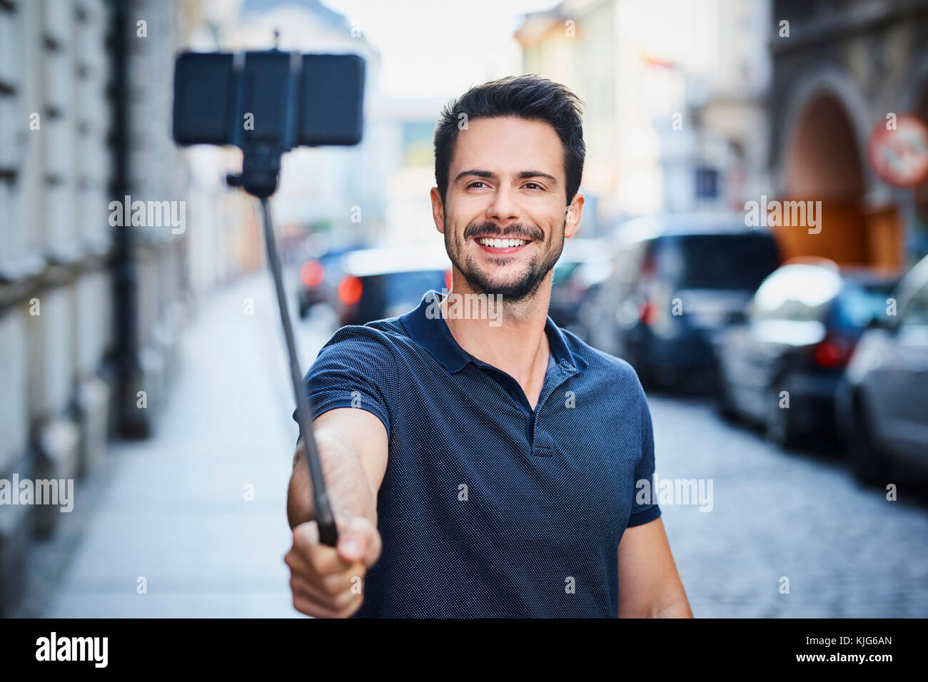 Man taking photo with smartphone mounted on selfie stick Stock Photo ...