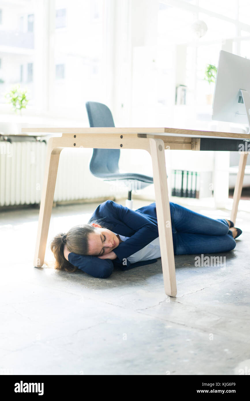 Businesswoman lying under the table in office sleeping Stock Photo - Alamy