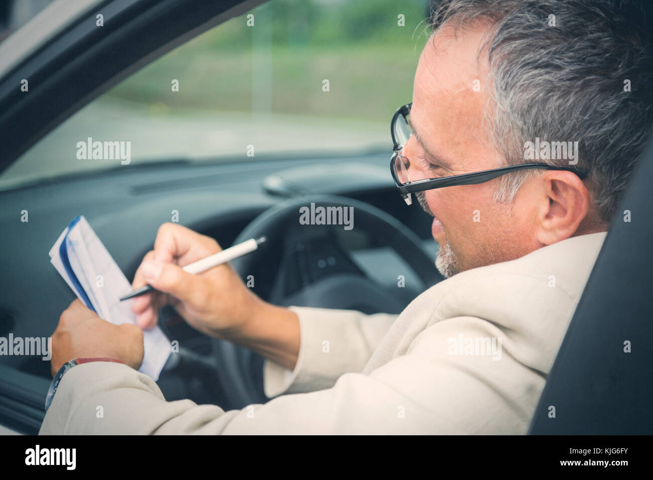 Businessman sitting in his car making notes Stock Photo - Alamy