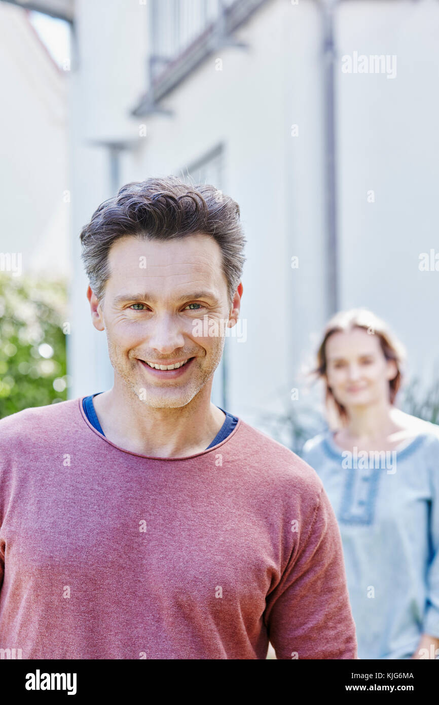 Portrait of smiling man with woman in background Stock Photo - Alamy