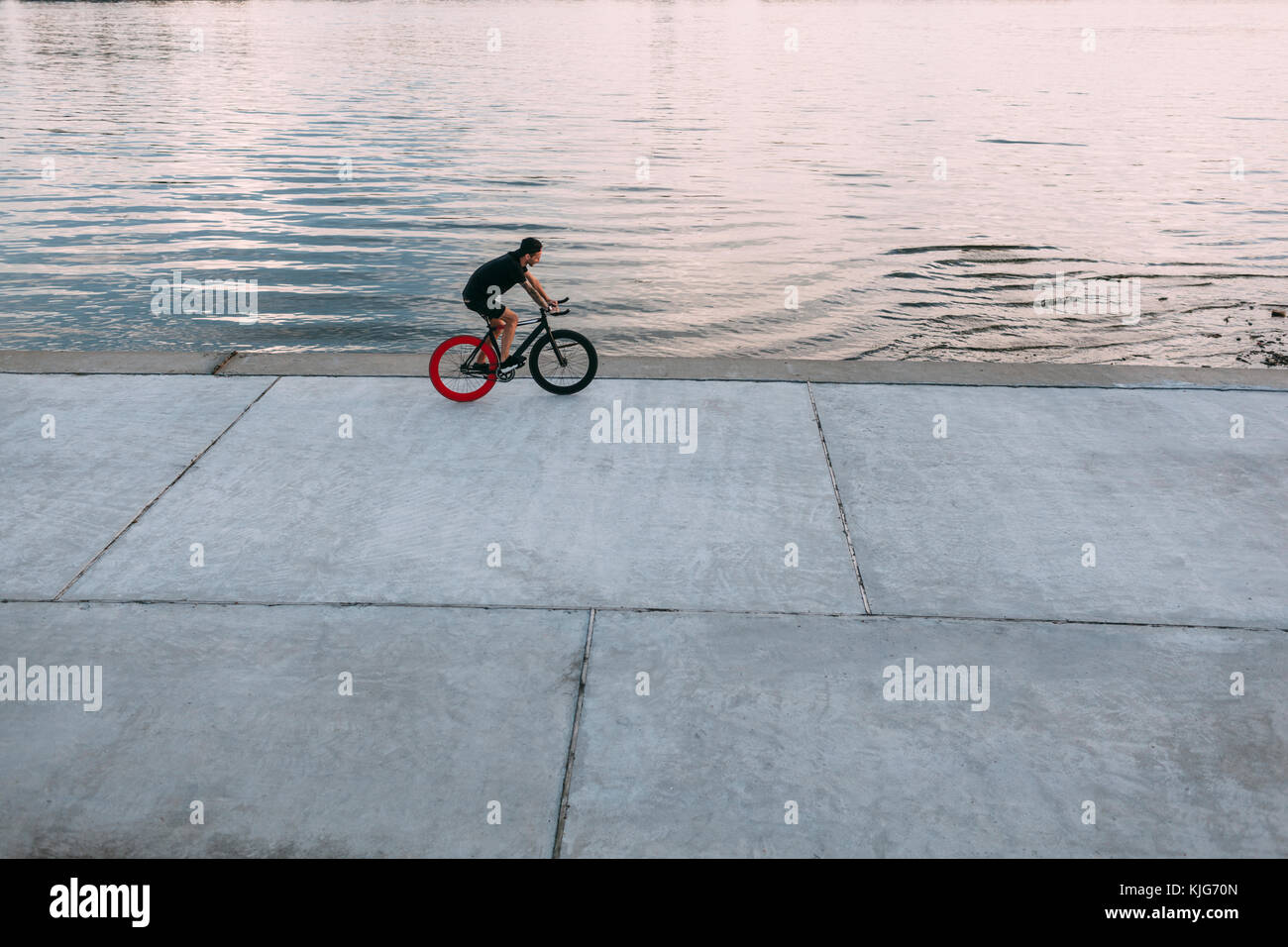 Young man riding fixie bike at the waterfront Stock Photo - Alamy
