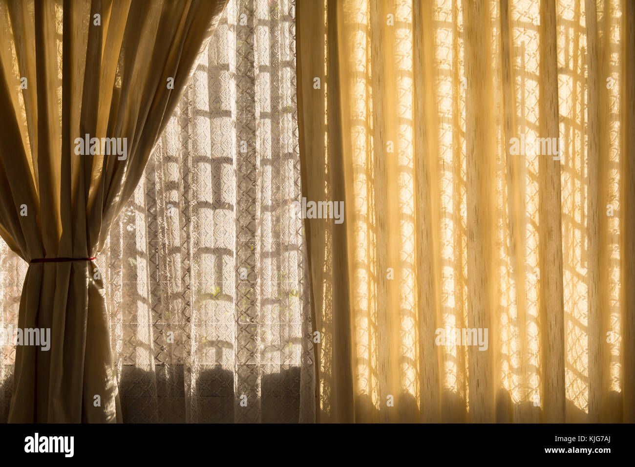 Sunlight from outside window streams into a room through thin lace ...