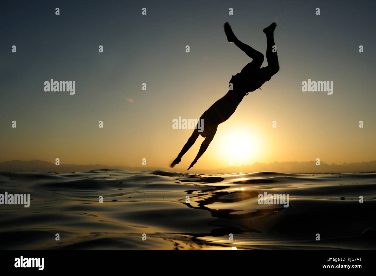 Man jumping into the sea at sunset Stock Photo - Alamy