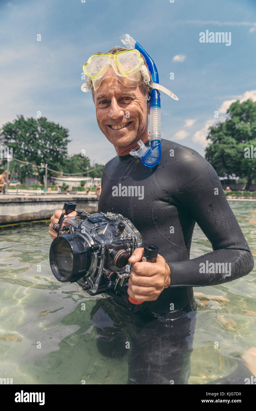 Portrait of happy man with underwater DSLR camera case in a lake Stock ...