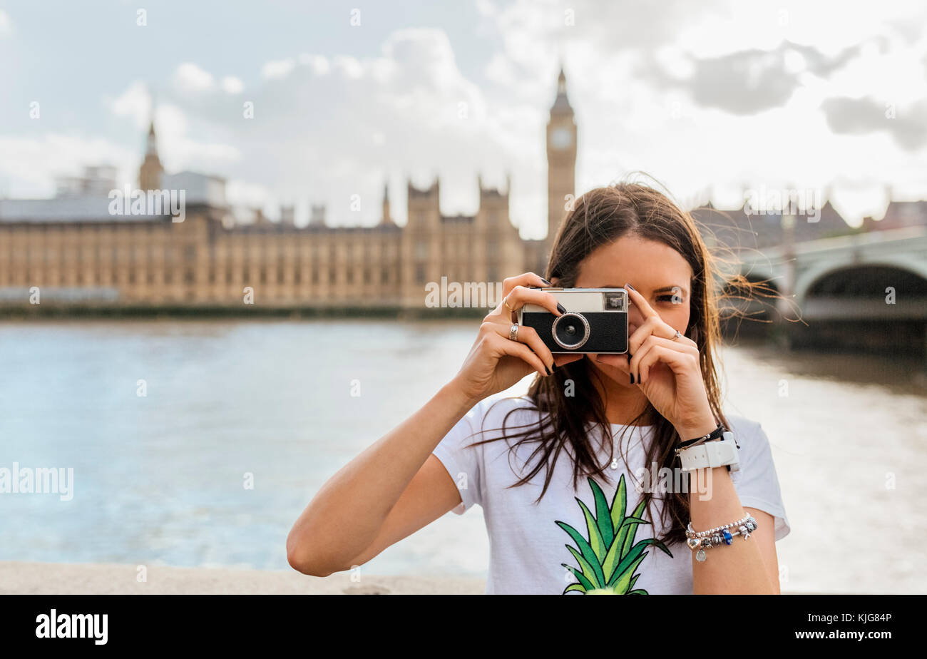 UK, London, beautiful woman taking a picture near Westminster Bridge ...
