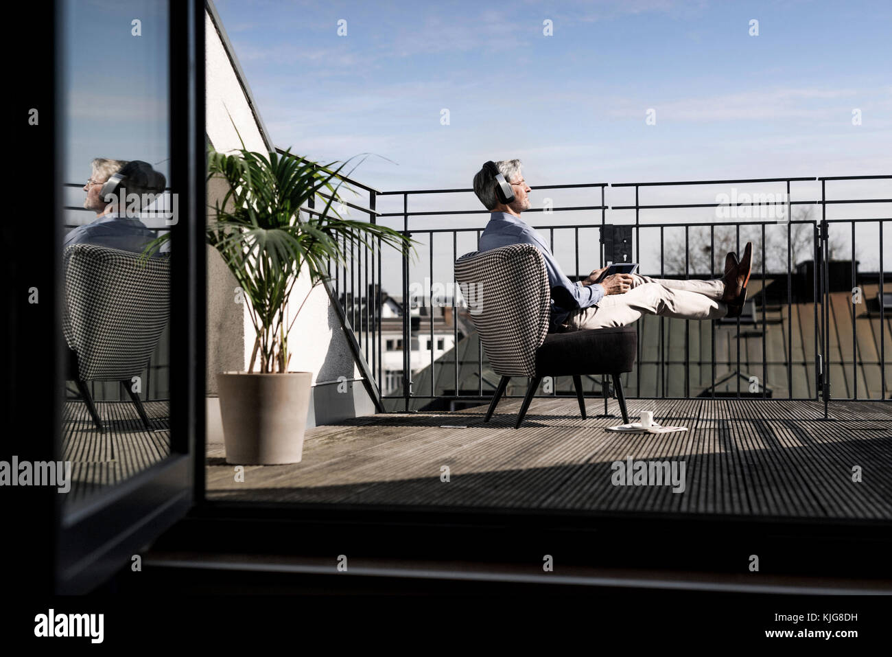 Grey-haired man relaxing in chair on balcony Stock Photo - Alamy