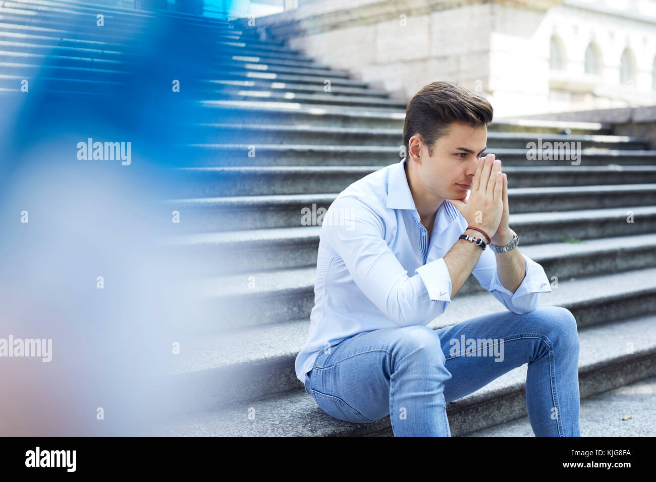 Pensive young man sitting on stairs Stock Photo - Alamy