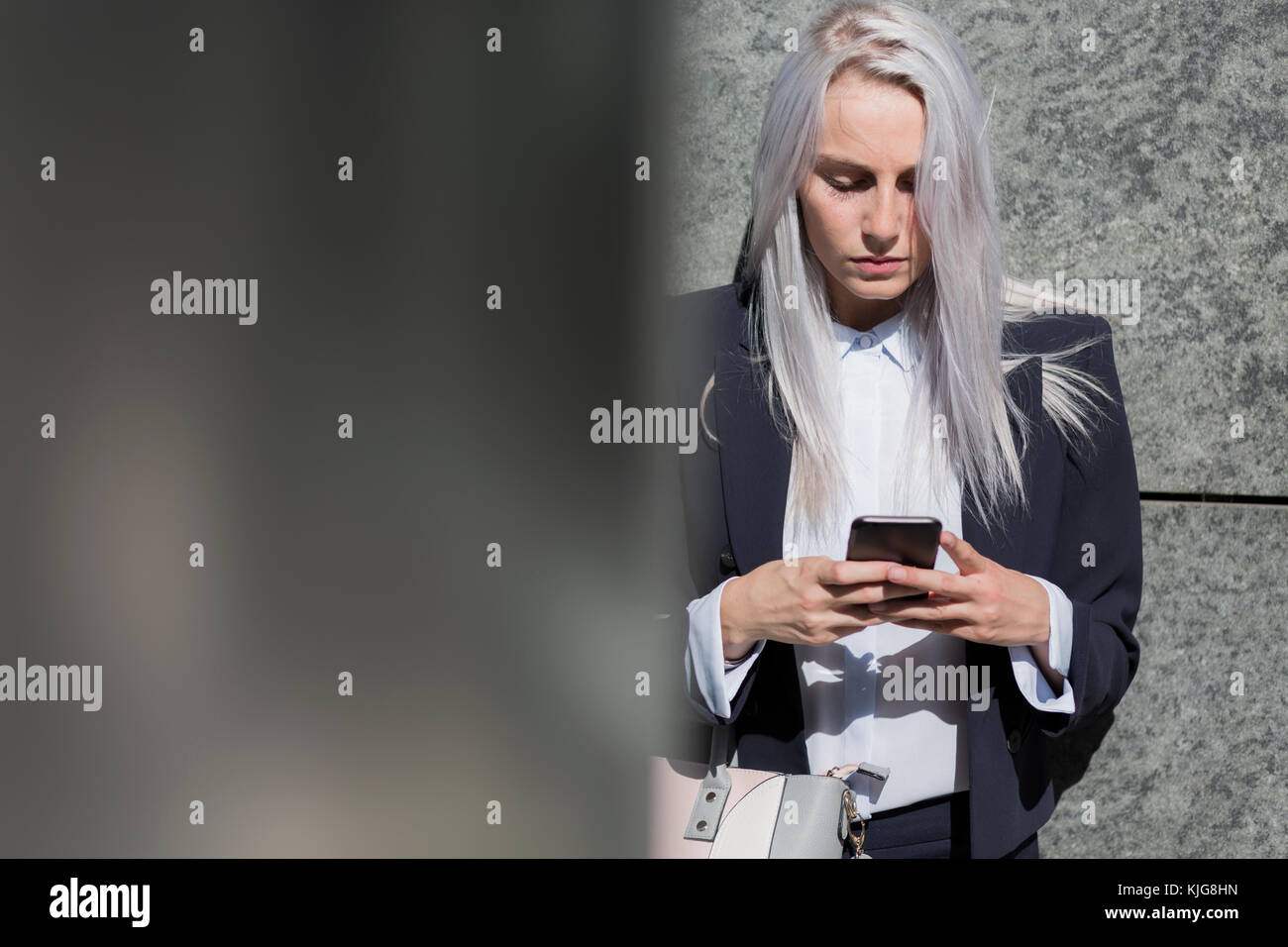 Young businesswoman checking cell phone in the city Stock Photo - Alamy