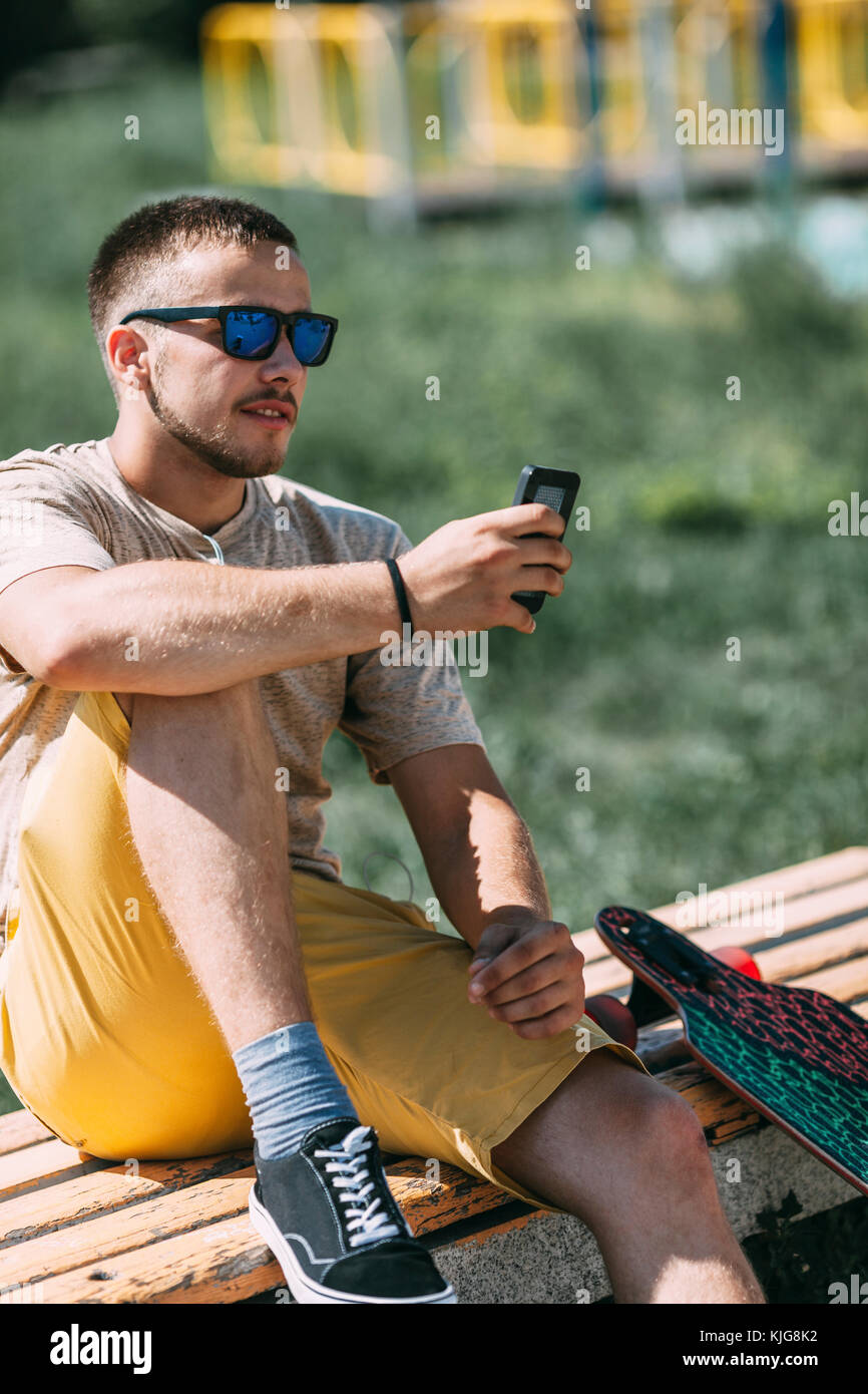 Young man sitting on a bench using cell phone Stock Photo - Alamy
