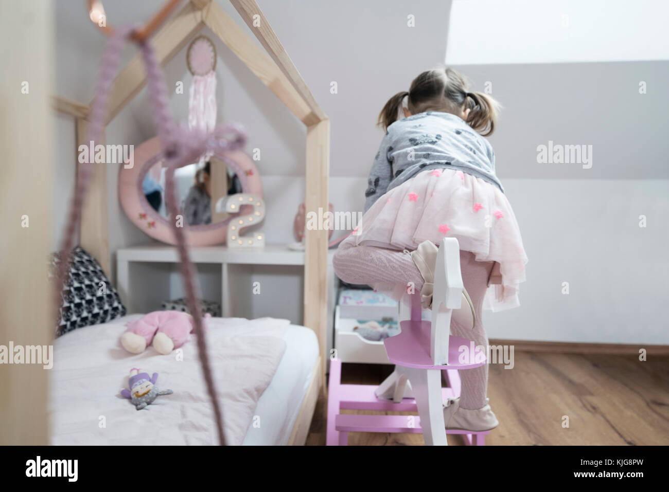 Toddler girl climbing on rocking horse in nursery Stock Photo - Alamy