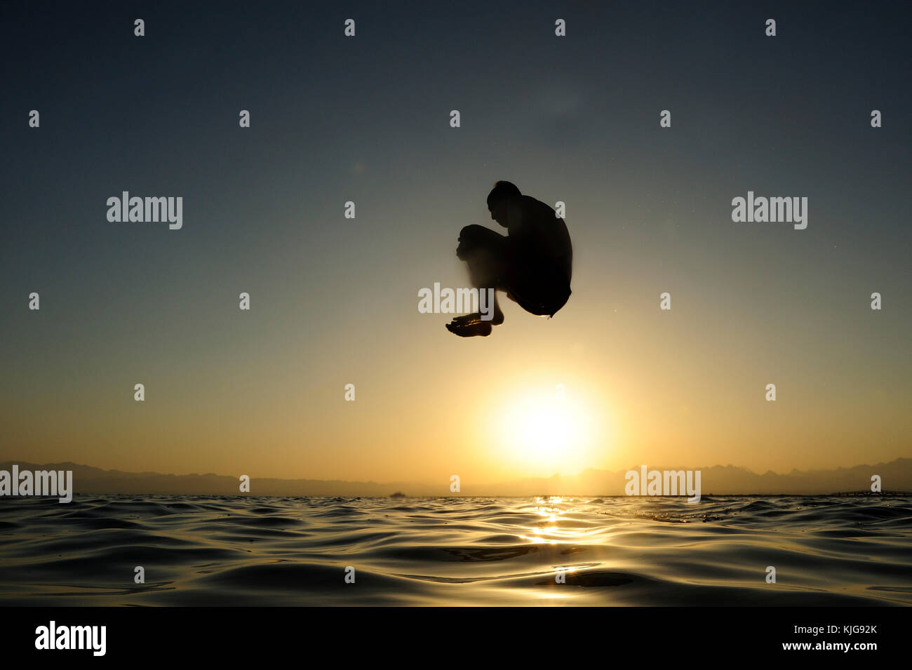 Man jumping into the sea at sunset Stock Photo - Alamy