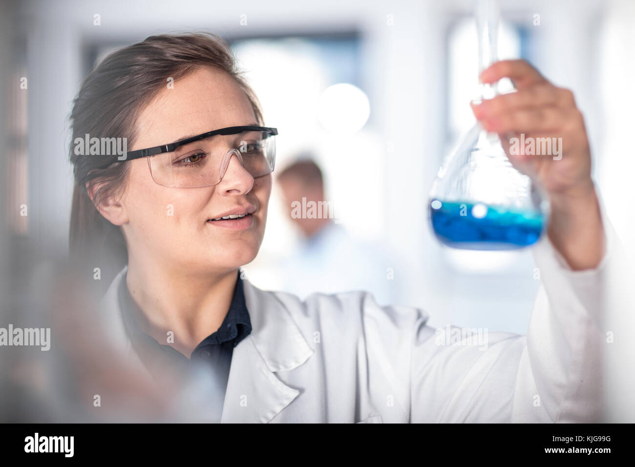 Scientist working in lab looking at flask Stock Photo - Alamy