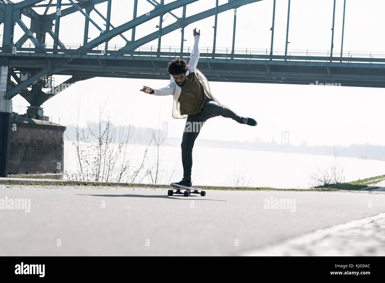 Young man balancing on longboard at the riverside Stock Photo - Alamy