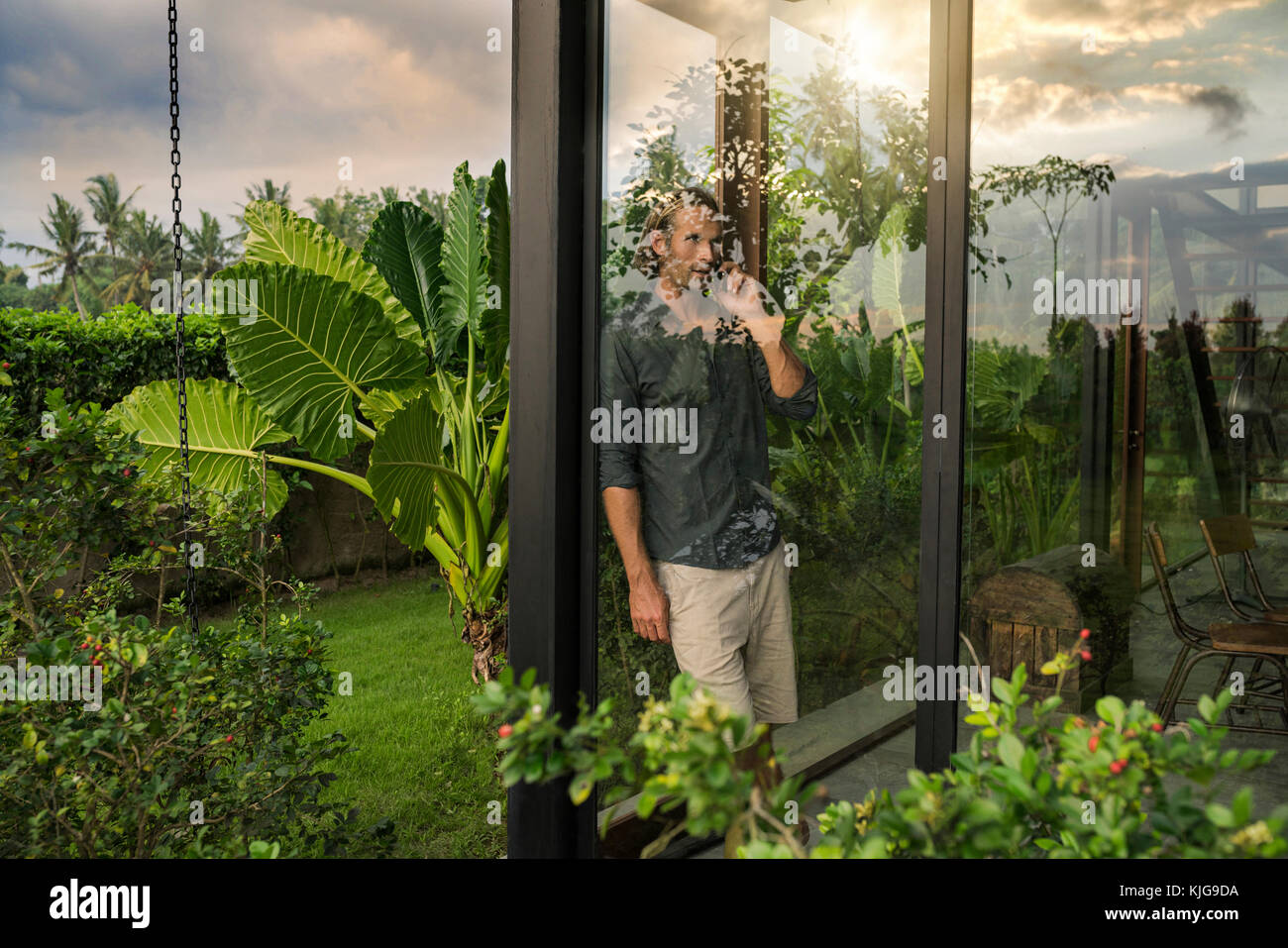 handsome man standing behind glass facade of design house talking on ...