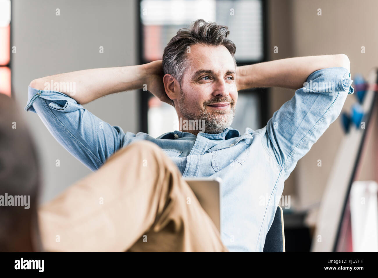 Businessman in office leaning back Stock Photo - Alamy
