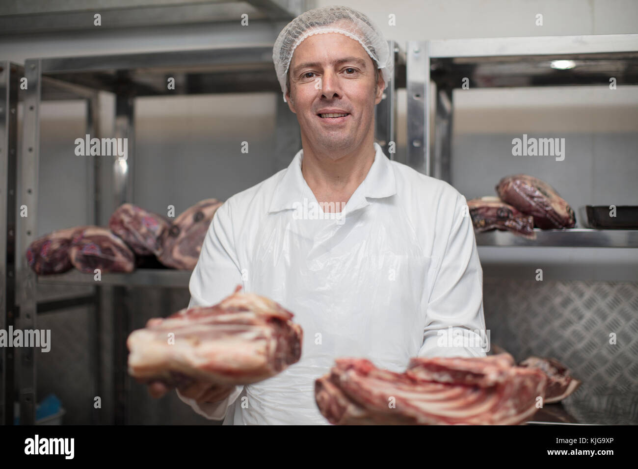 Portrait of smiling butcher holding meat Stock Photo - Alamy