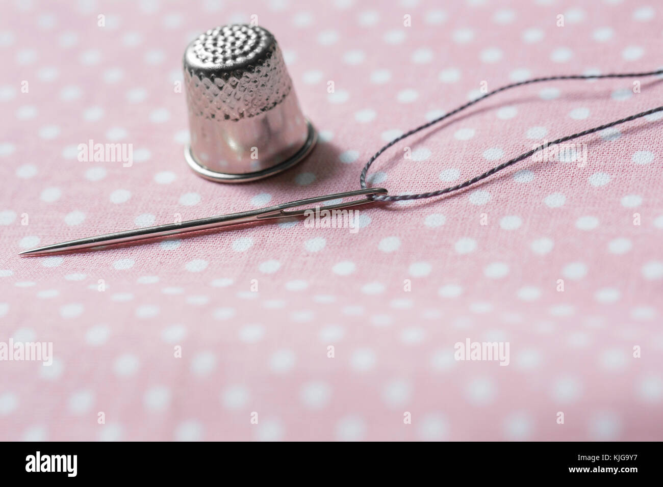 Thimble, needle and thread on cloth Stock Photo - Alamy