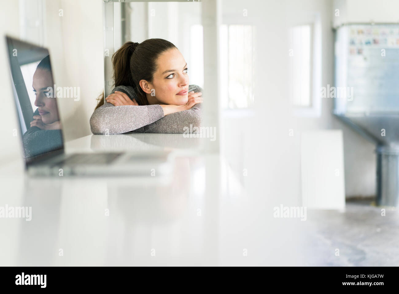 Woman leaning on desk with laptop Stock Photo - Alamy