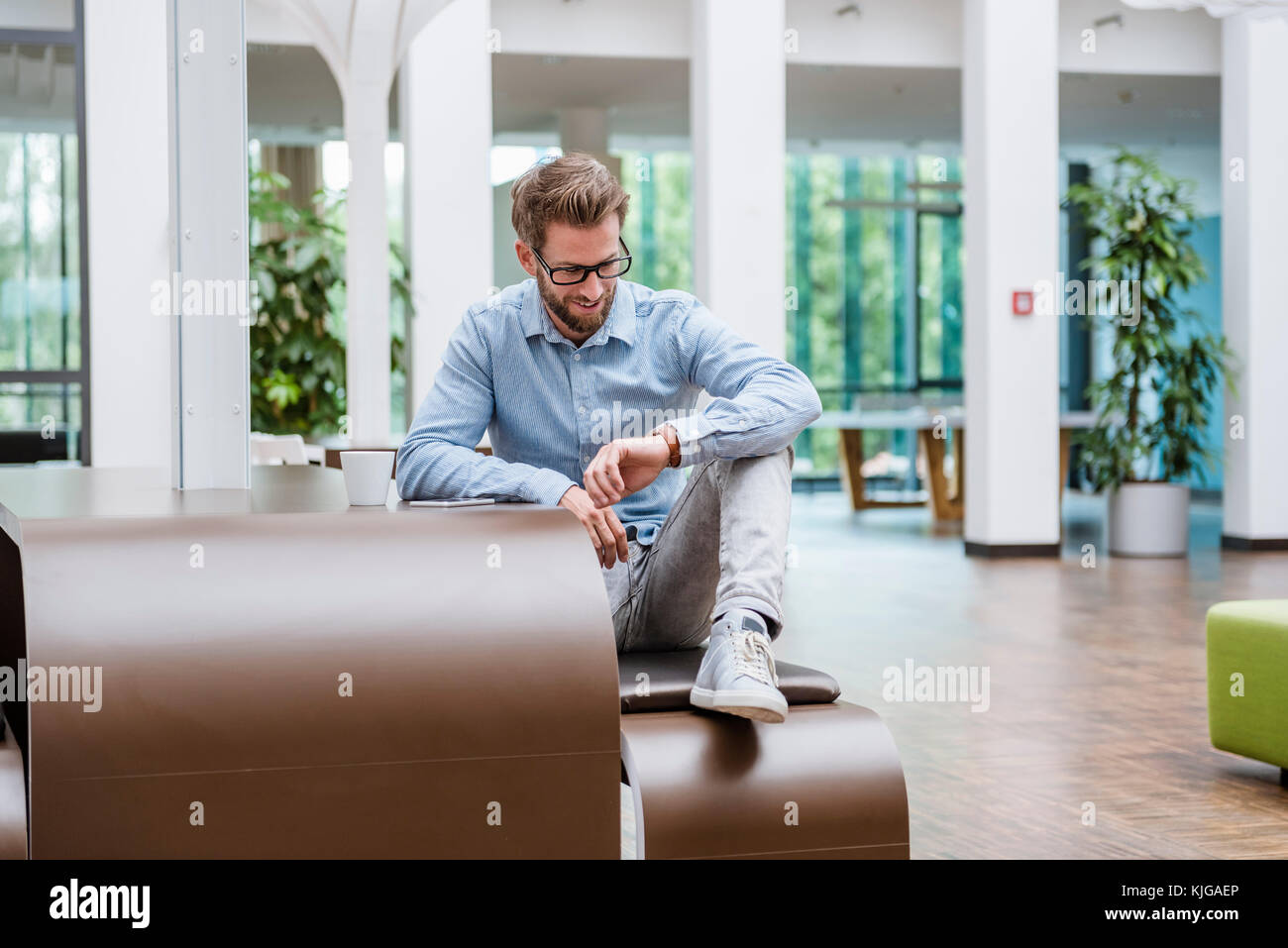 Smiling man checking the time in modern office Stock Photo - Alamy
