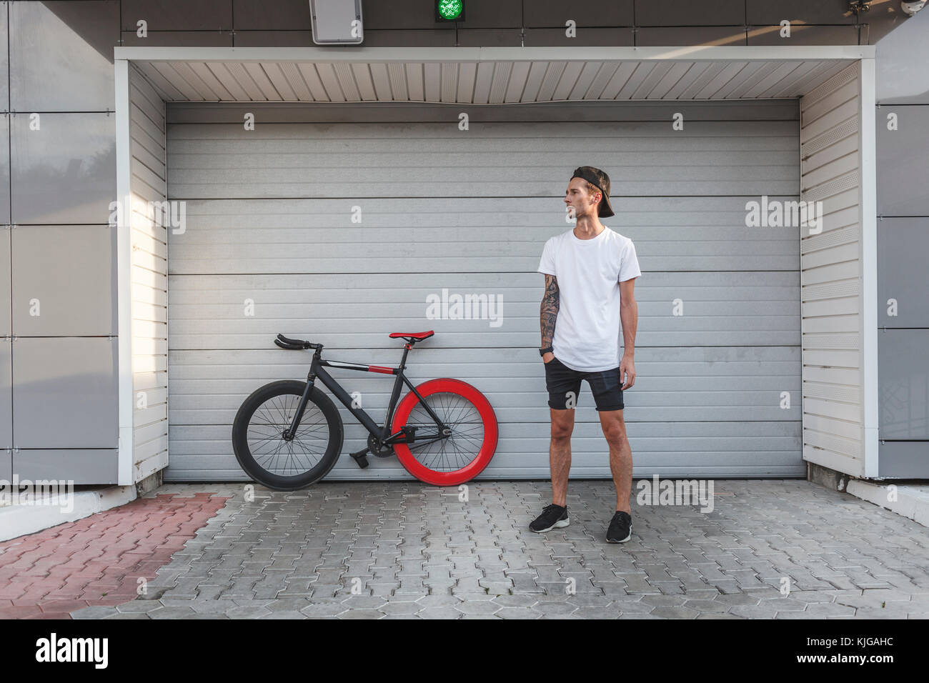 Young man with fixie bike at a roller shutter Stock Photo - Alamy
