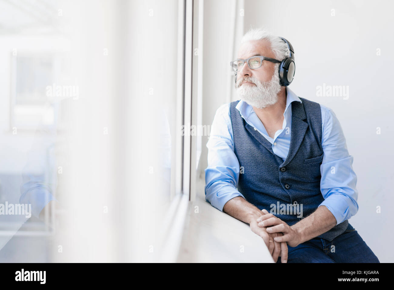 Mature man wearing glasses and headphones looking out of window Stock ...
