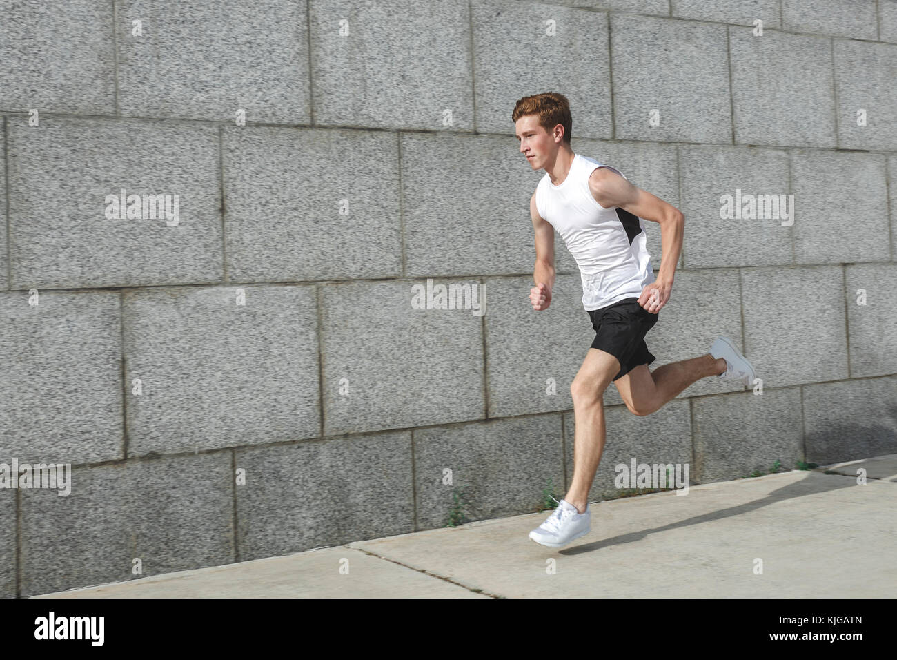 Young man running along wall Stock Photo - Alamy