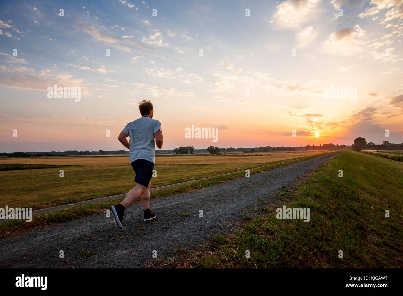 Man running in rural landscape at sunset Stock Photo - Alamy