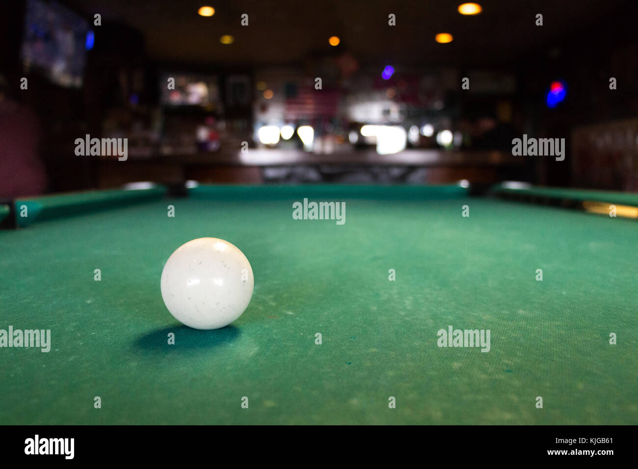 A white pool ball isolated on the pool table, bar blurred background ...