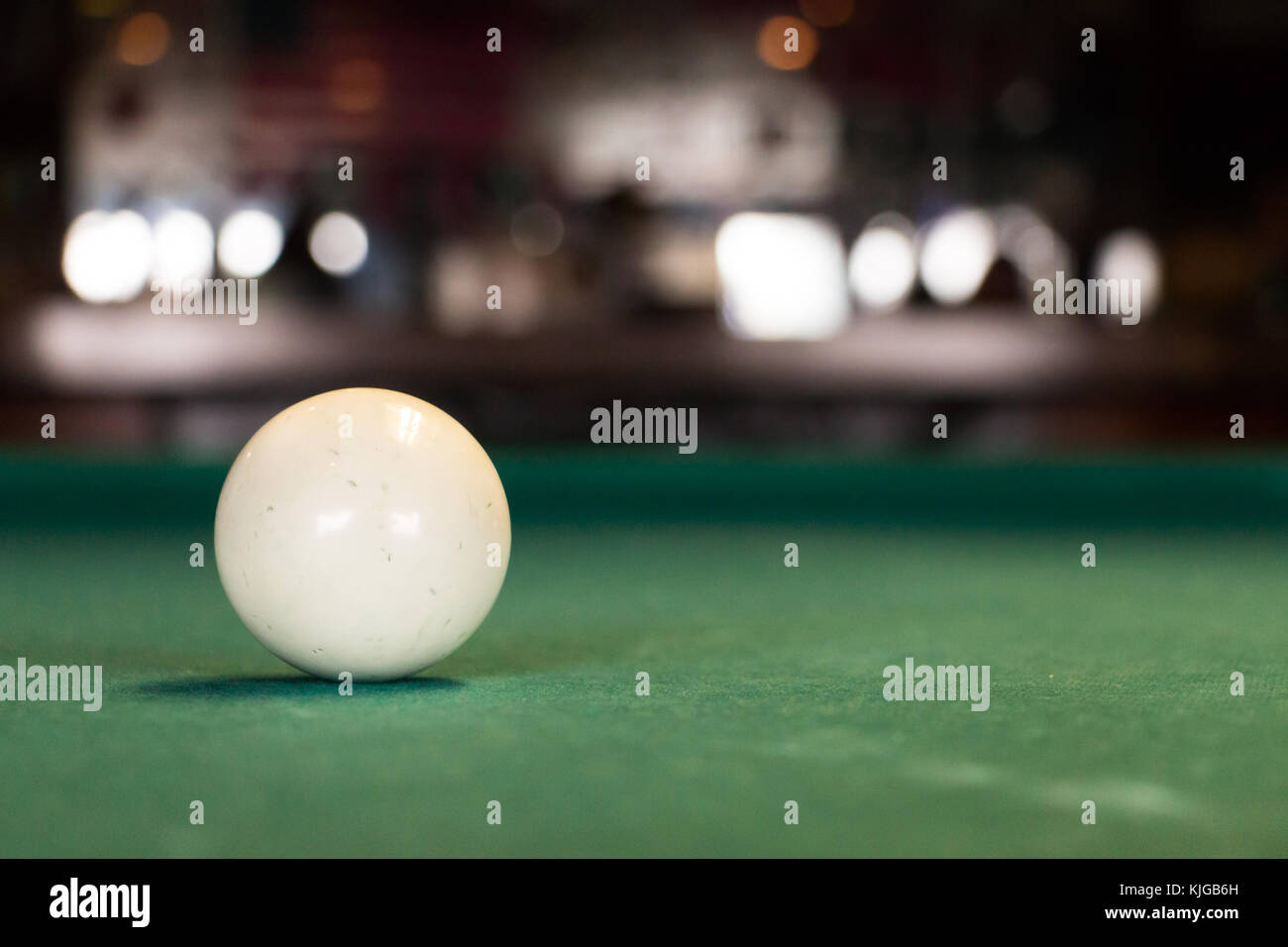 A white pool ball closeup, isolated, on the pool table, bar blurred ...