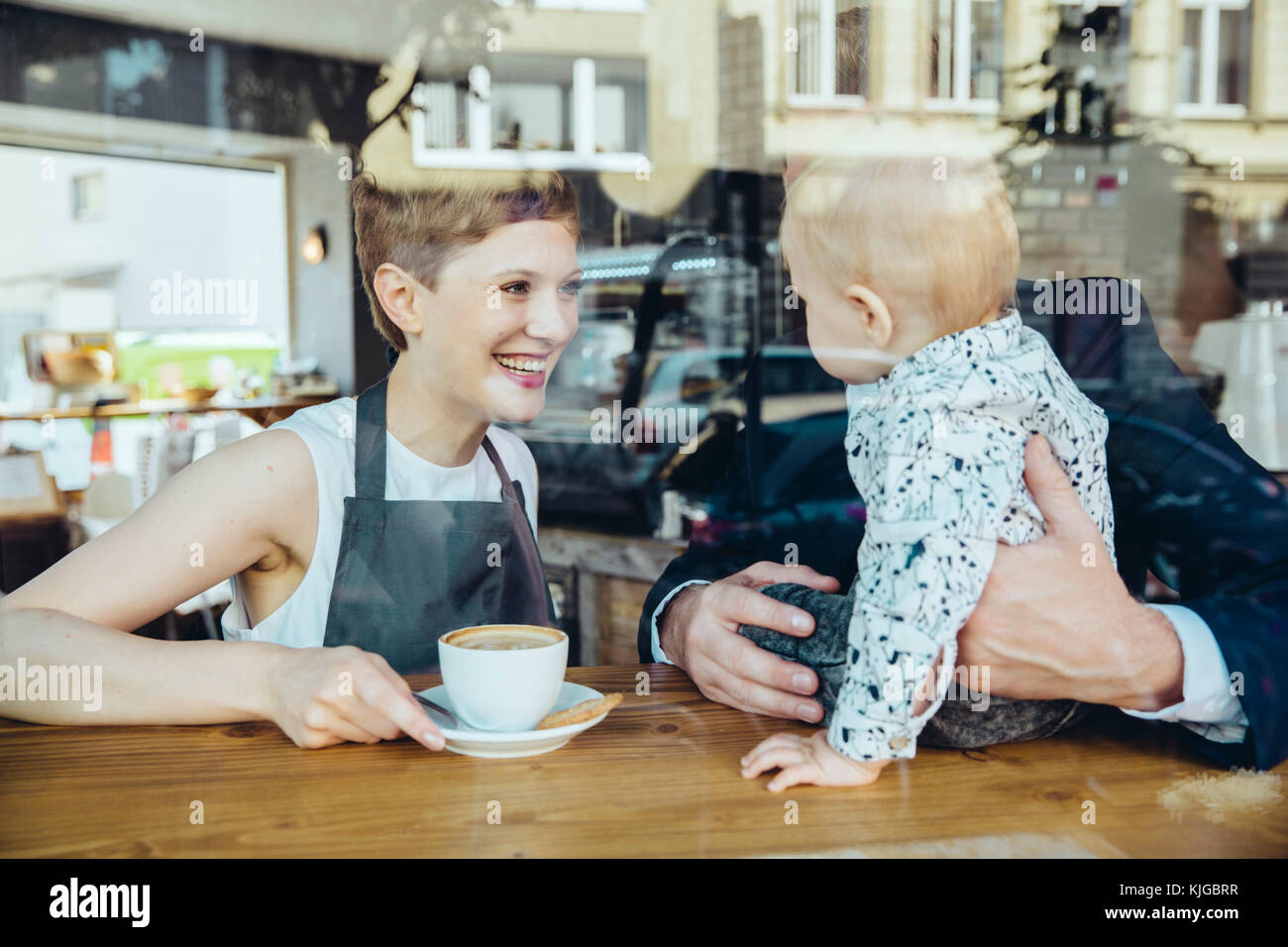 Waitress serving coffee to smiling customer with baby in cafe Stock ...