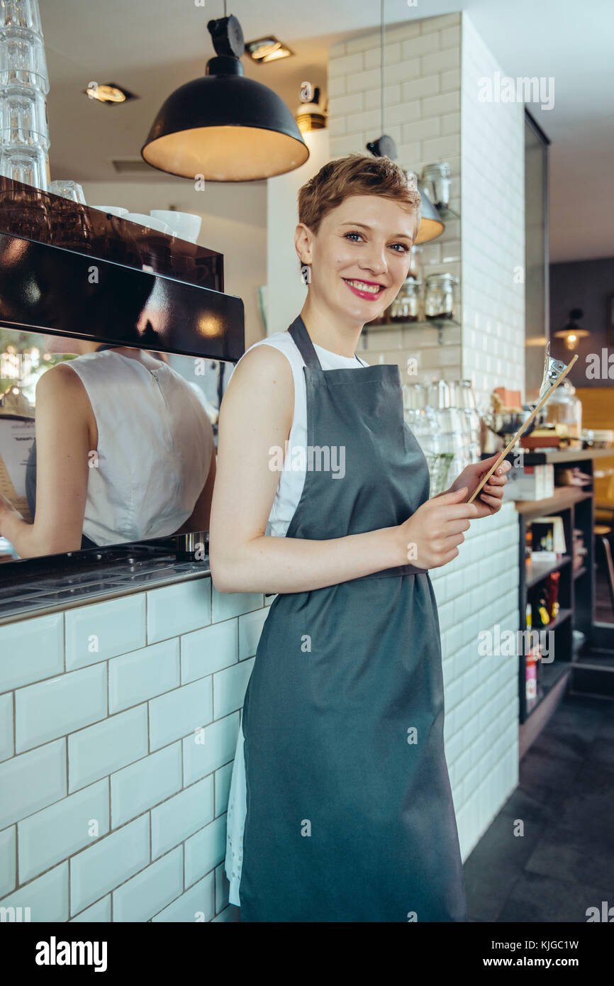 Portrait of smiling waitress holding menu in a cafe Stock Photo - Alamy