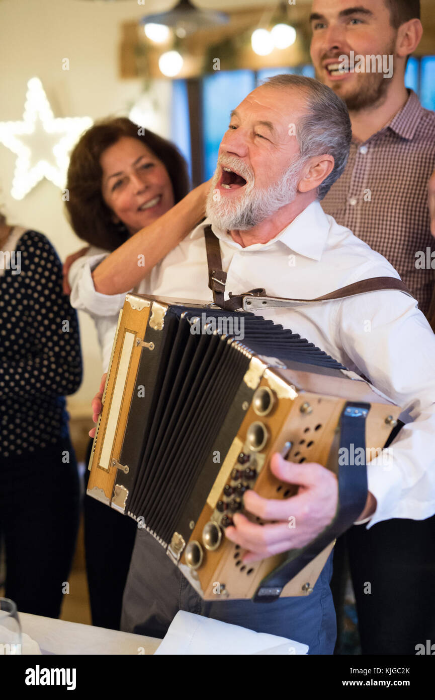 Senior man playing accordion for happy family at Christmas Stock Photo ...