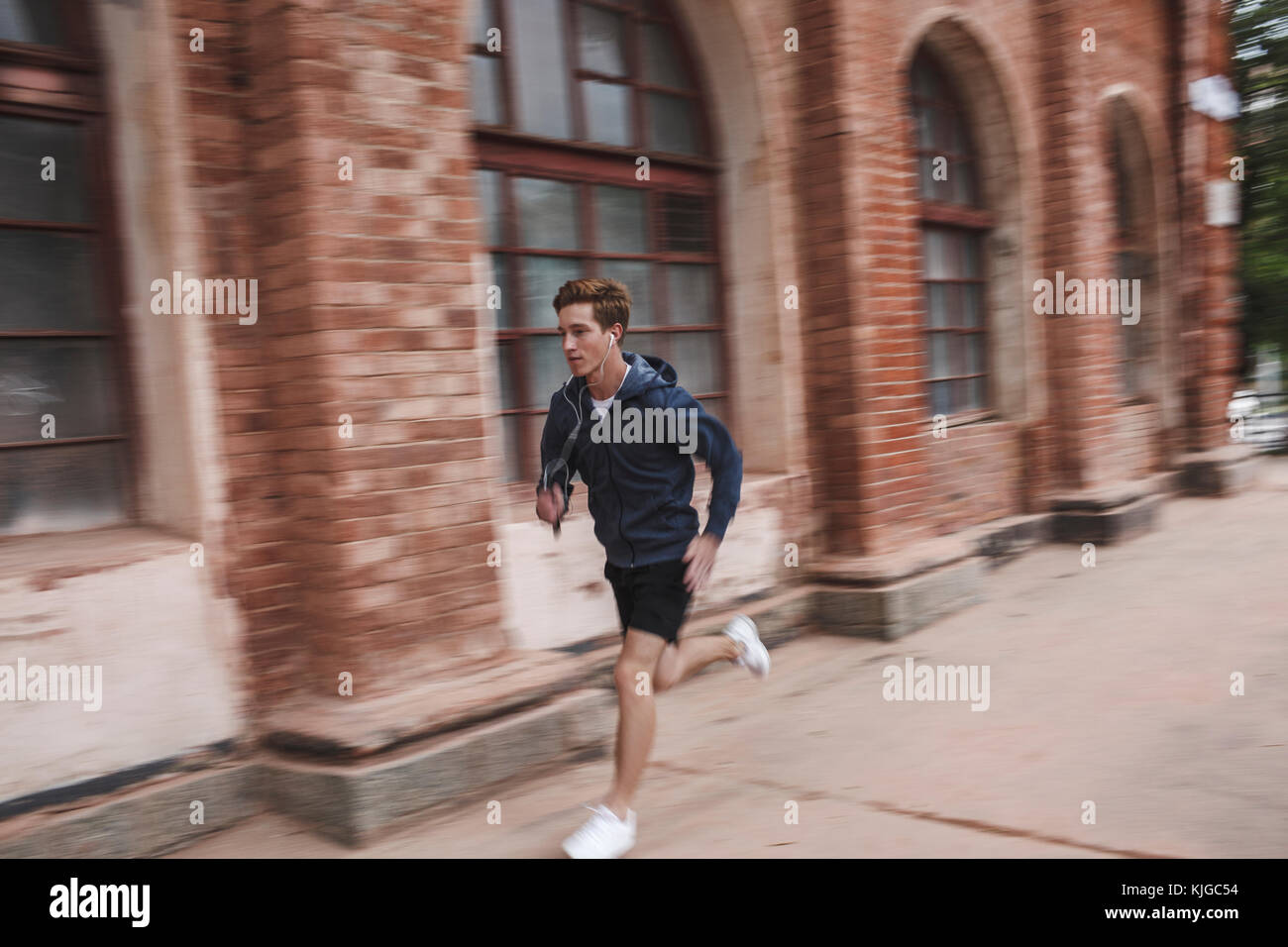 Young man running along brick building Stock Photo - Alamy