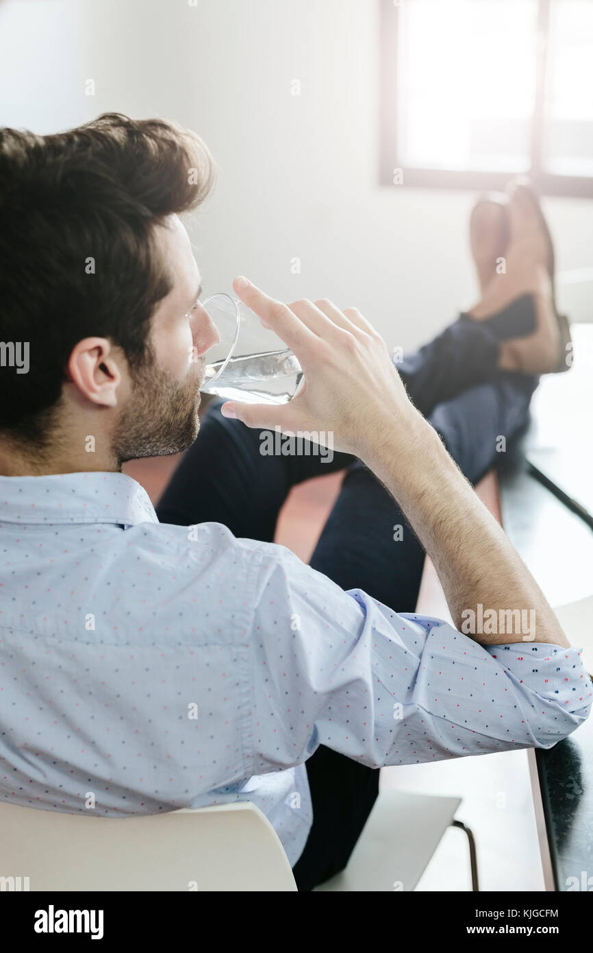 Young businessman working in office, drinking water Stock Photo - Alamy