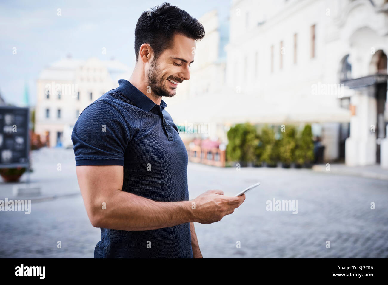 Smiling man using cell phone in the city Stock Photo - Alamy