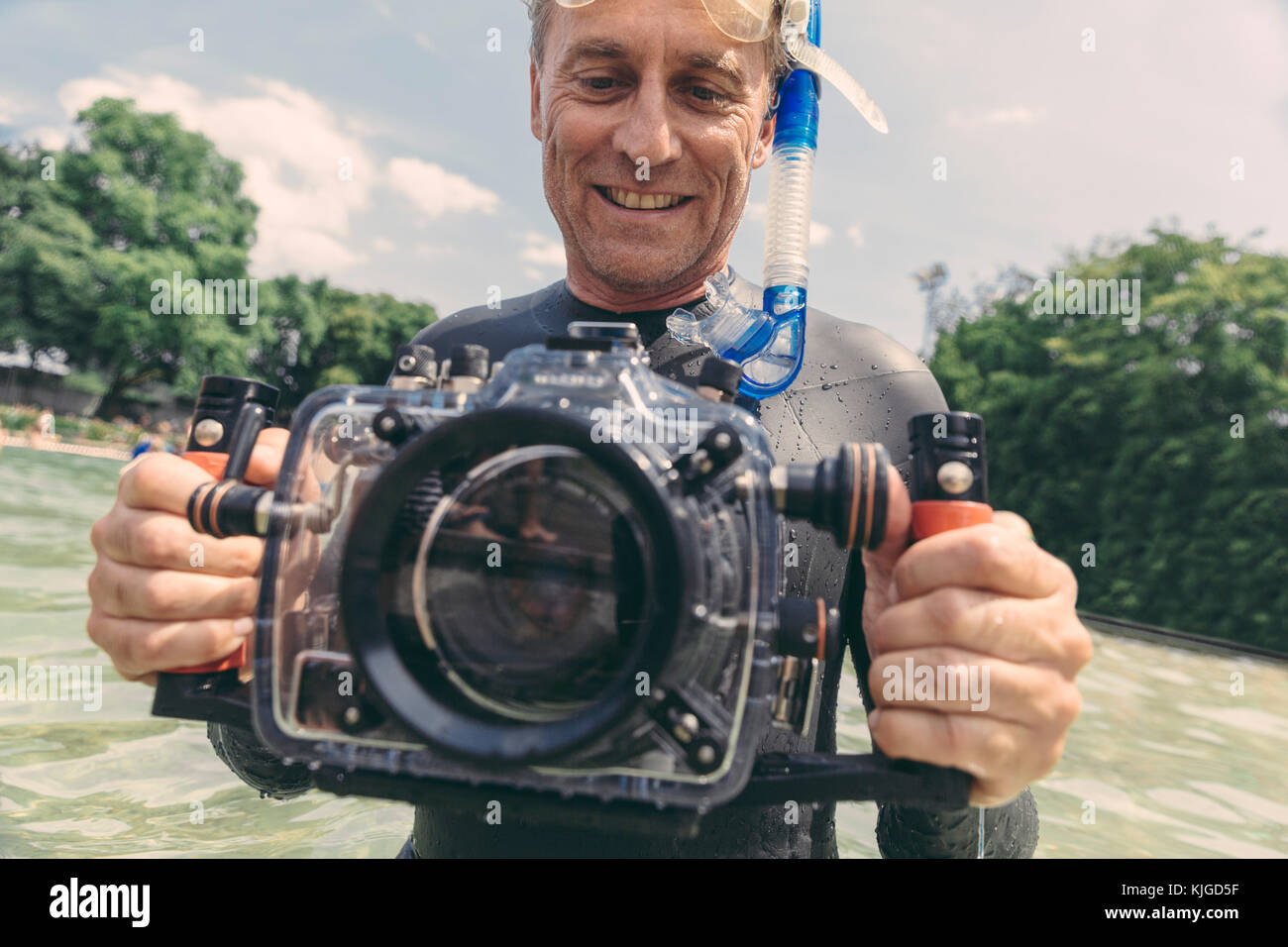 Smiling man holding underwater DSLR camera case in a lake Stock Photo ...