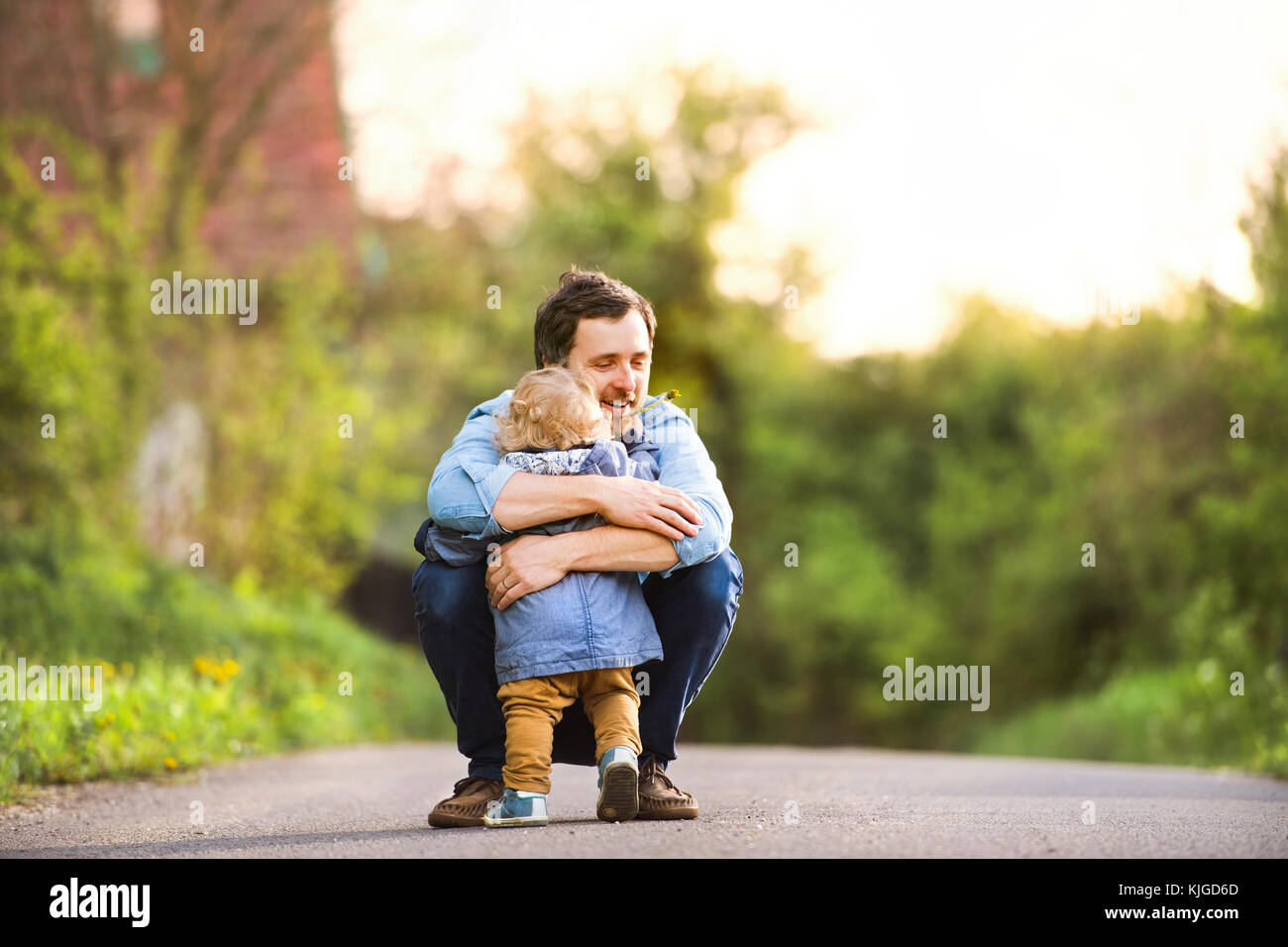 Father hugging little boy on field path Stock Photo - Alamy